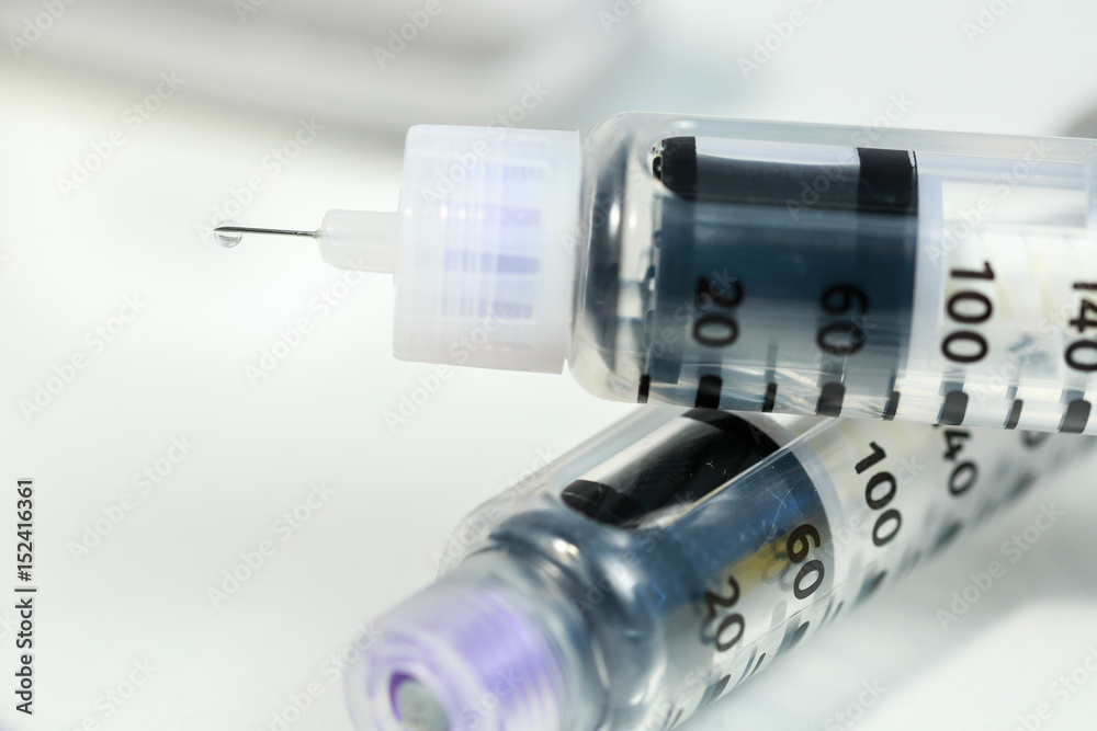 Empty insulin pens on white. Drop of insulin on the needle of one of ...