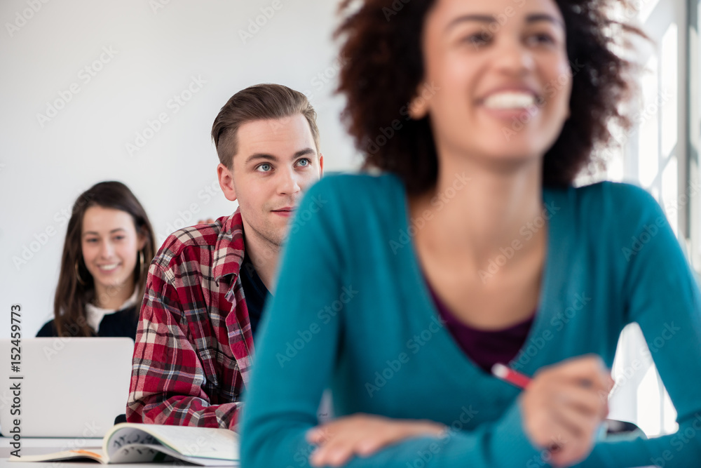 Student smiling while using a tablet during class in a modern college ...