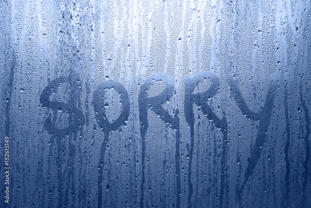 Conceptual sorry word handwritten message on the rainy glass window ...