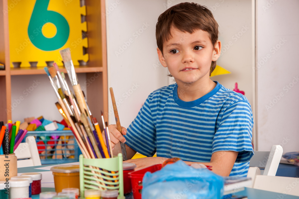 Small student boy painting in art school class. Child drawing by paints ...