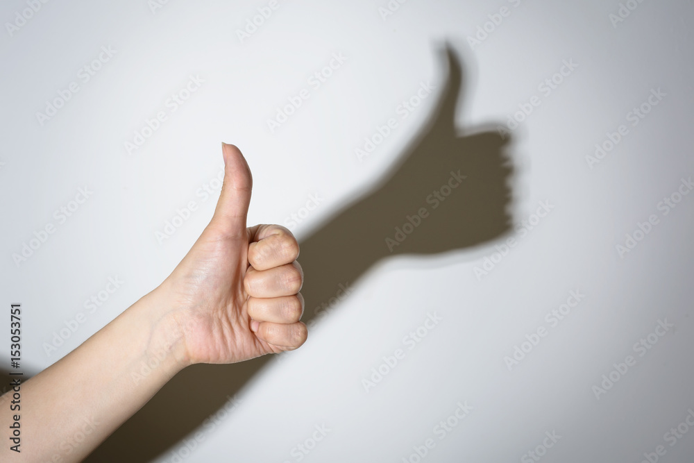 Woman's hand show thumbs up sign. Shadow on the wall Stock Photo ...