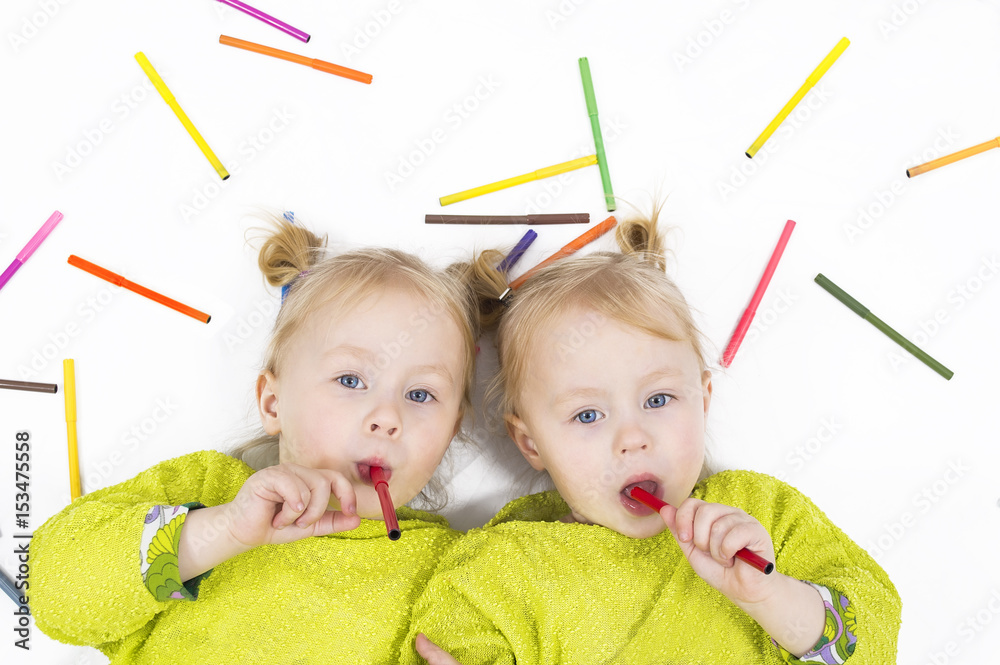 Two identical beautiful twins girls having fun on a white background ...