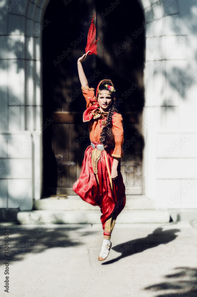beautiful girl in traditional Turkish costume plays and jumps with a ...
