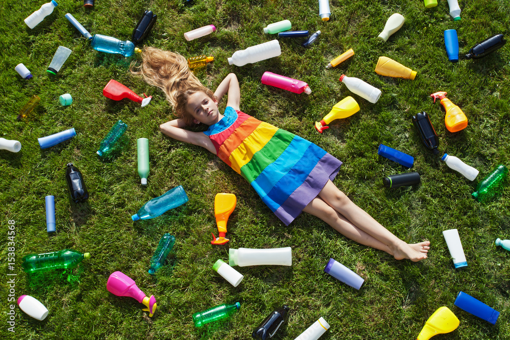 Sad little girl lying on the garbage filled grass Stock Photo | Adobe Stock