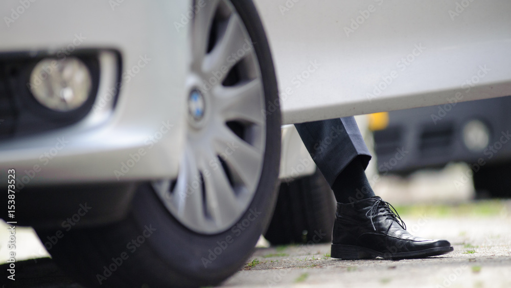 Business man's feet standing next to the car, in the open doorway of ...