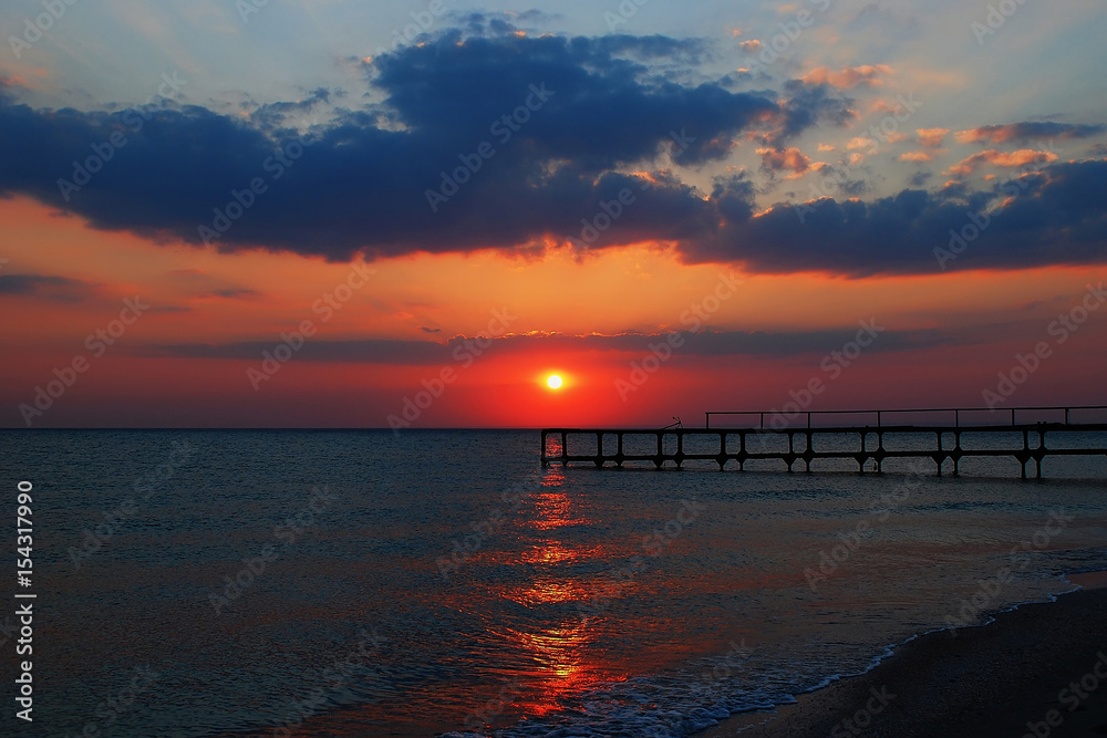 Golden natural sea sunset view of small bridge at horizon and red sky ...