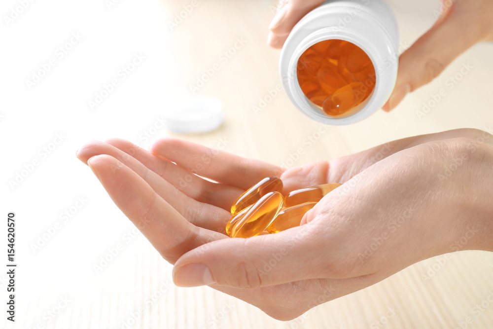 Woman pouring fish oil capsules from bottle, close up Stock Photo ...