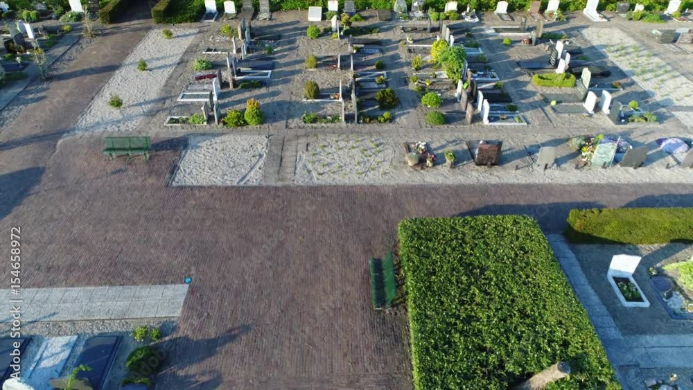 Aerial camera tilted down flying backwards over graveyard showing the ...