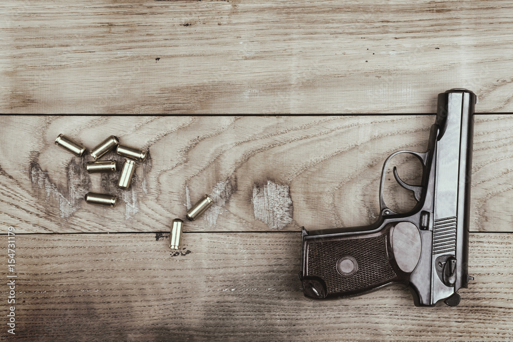 Traumatic pistol with bullets and cartridge on the wooden surface ...