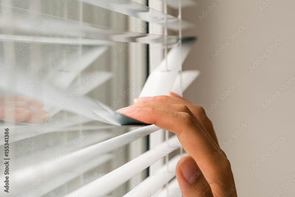 Windows jalousie. woman peeking through window blinds. Male hand ...
