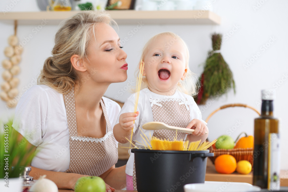 Mother kiss her child daughter while cooking pasta for the breakfast ... Mother kiss her child daughter while cooking pasta for the breakfast ...
