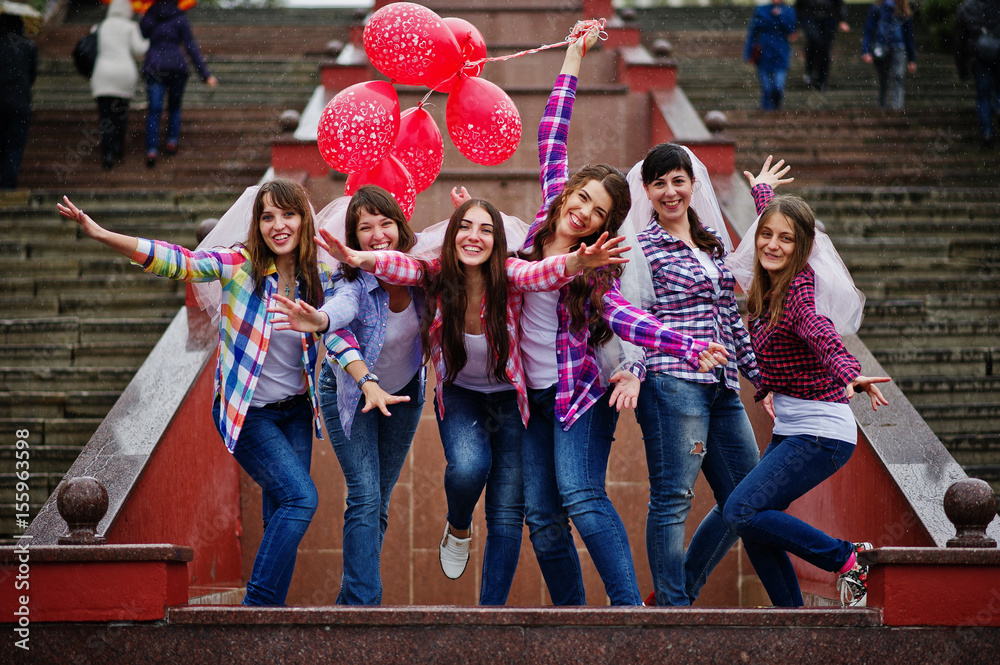 Group of six girls having fun at hen party, with balloons under rain at ...