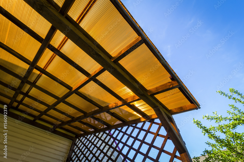 The roof of the veranda of orange polycarbonate on blue sky background ...