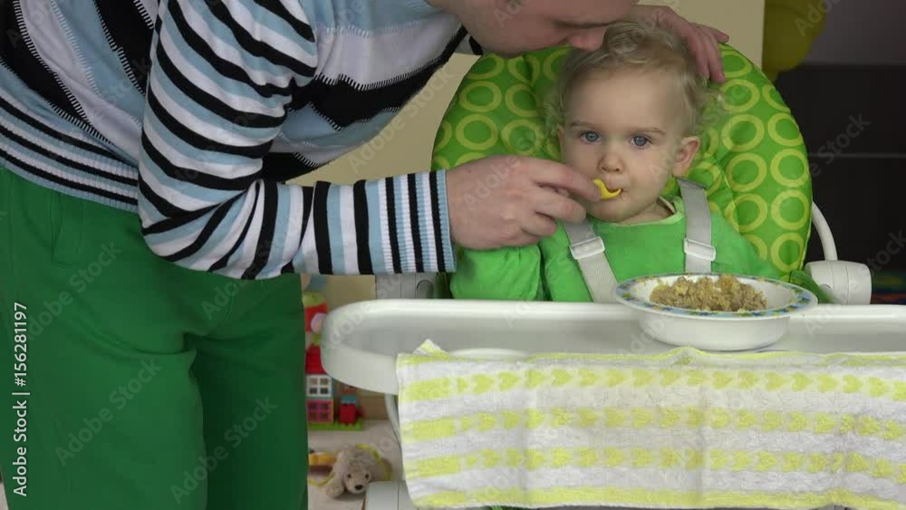 father learn baby girl eat gruel with spoon sit on highchair. 4K Stock ...