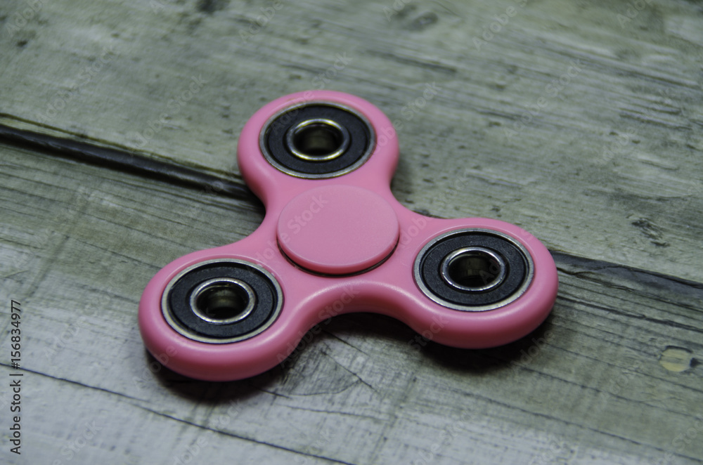 Pink fidget spinner isolated on a wooden table. Stock Photo | Adobe Stock