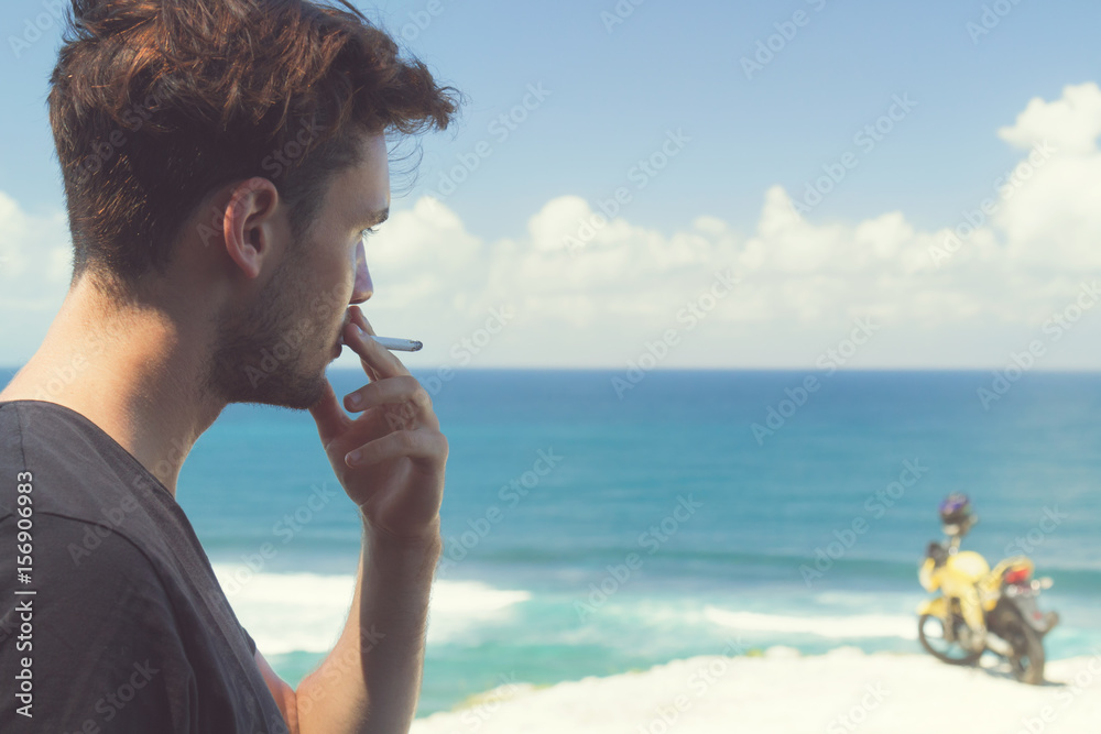 Handsome young man relaxing and smoking cigar on the beach. Stock Photo ...