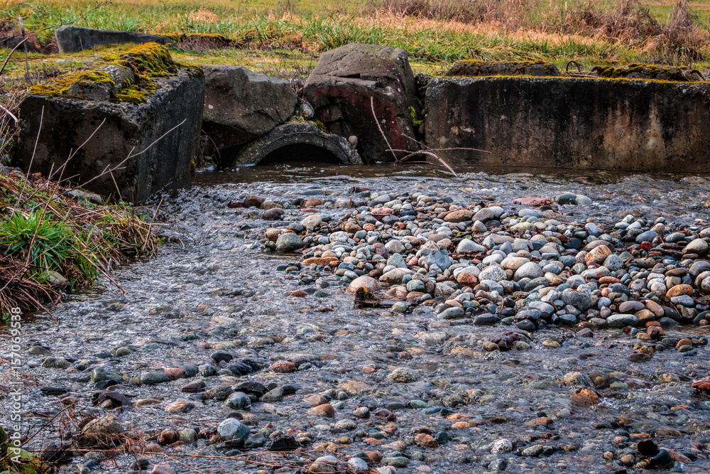 Water flow under field culvert with stone head gate and rocky bottom ...