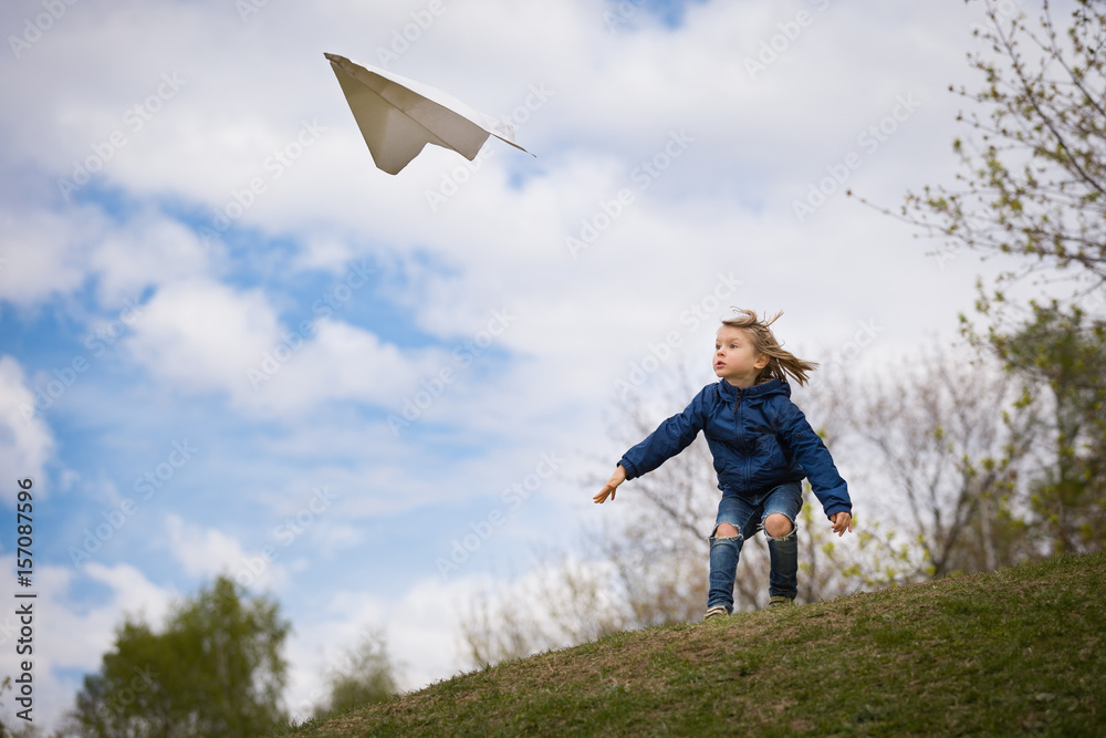 Cute kid boy launching paper airplane in the park. Small child having ...