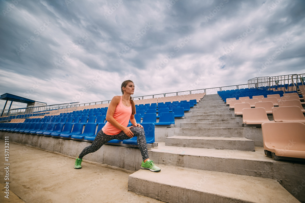 Beautiful muscular girl running around the stairs at the stadium ...