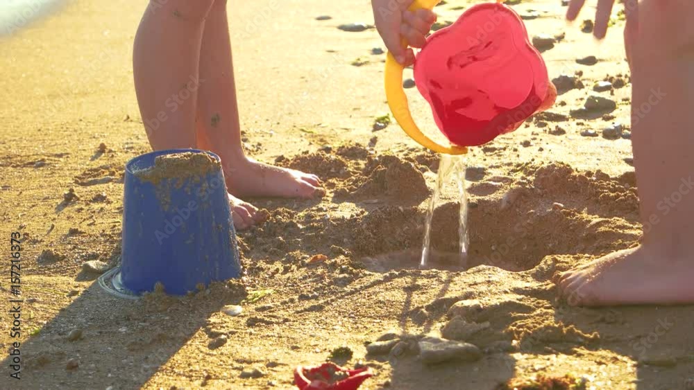 Kid pouring water from bucket. Leg of child stomping mud. Behavior ...
