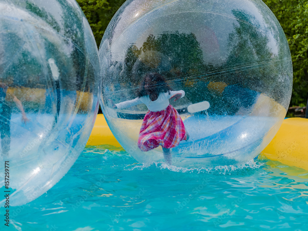 Cute girl in inflatable bubble at water amusement park. Children ...