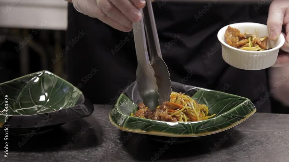 Man puts dish of pasta on plate standing at table in kitchen. Young ...