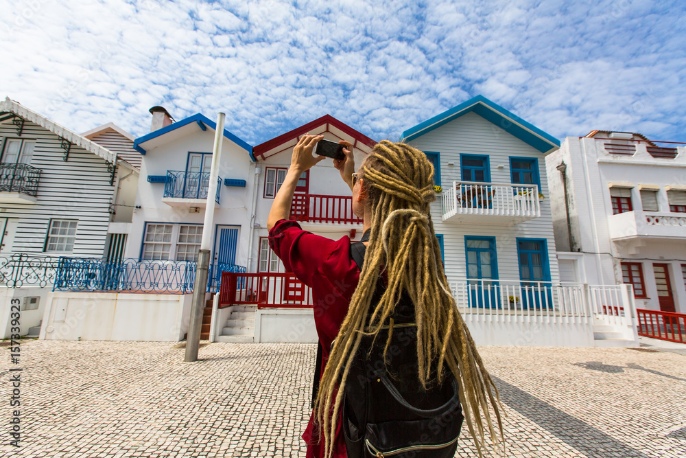 Young woman tourist taking photo on phone striped houses in Costa Nova ...