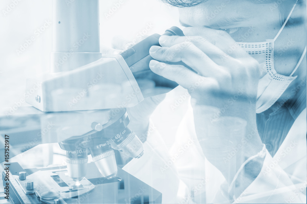 Asian scientist looks into microscope for chemistry test samples ...