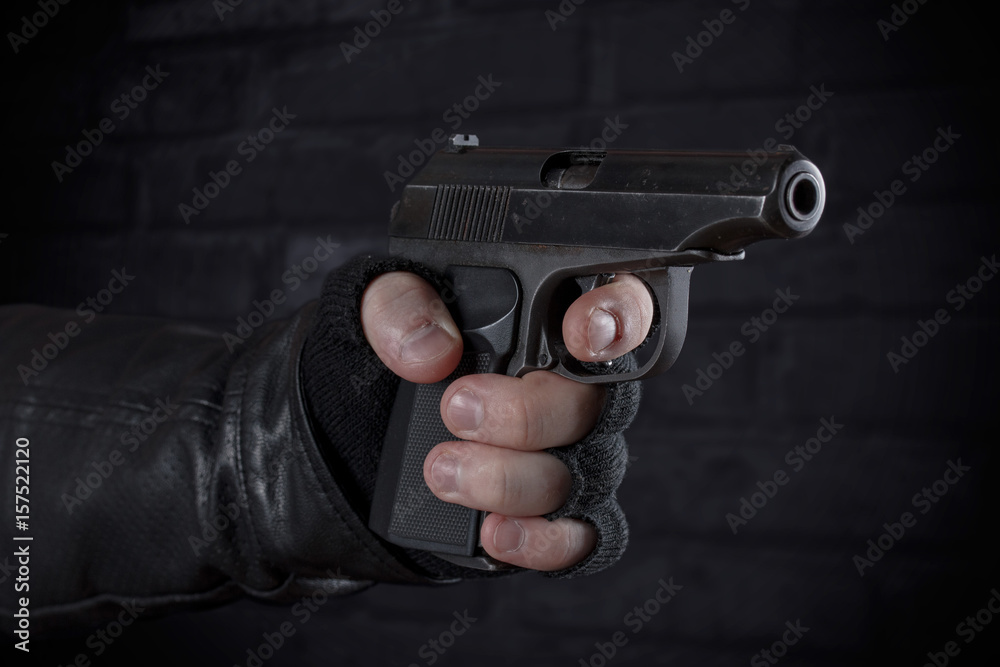 Gangster with a gun in his hand and a leather jacket on a dark ...
