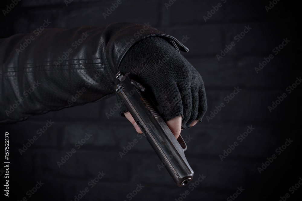 Gangster with a gun in his hand and a leather jacket on a dark ...