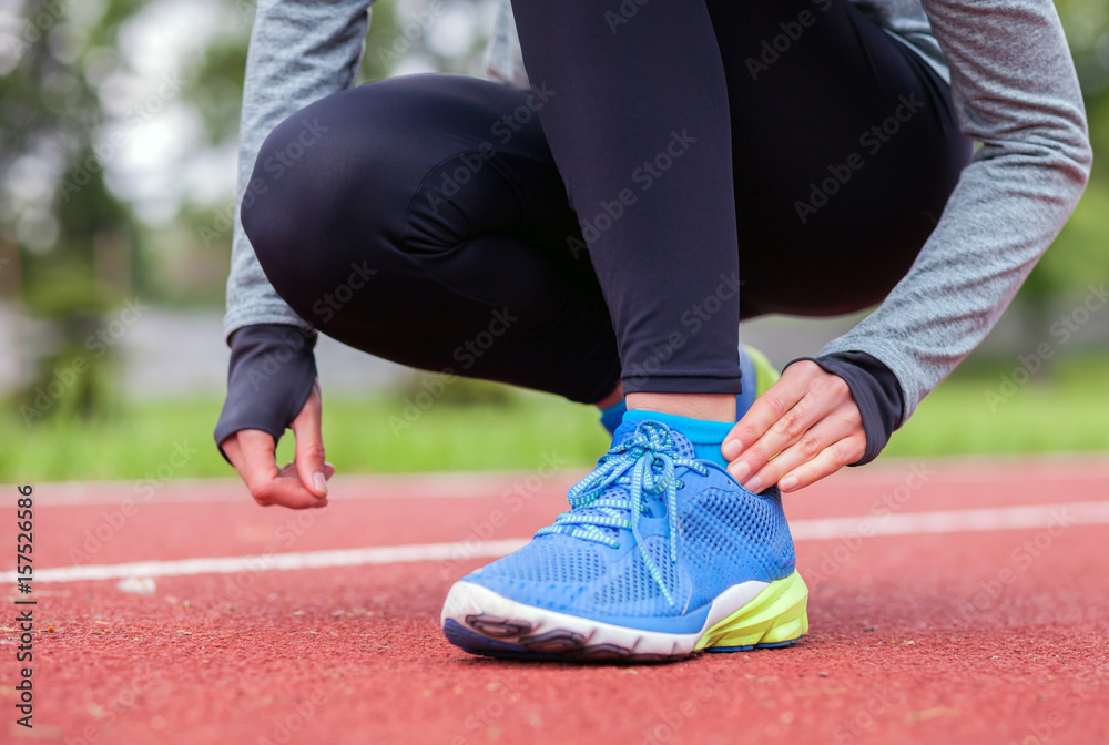 Athletic woman on running track touching hurt leg with ankle injury ...