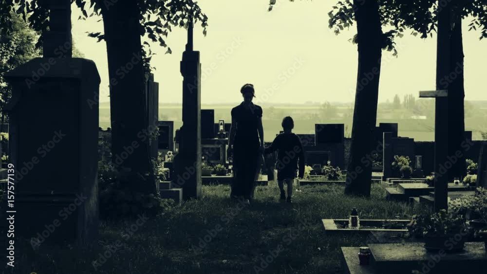Woman with small boy in cemetery goes straight to camera. Mother and ...