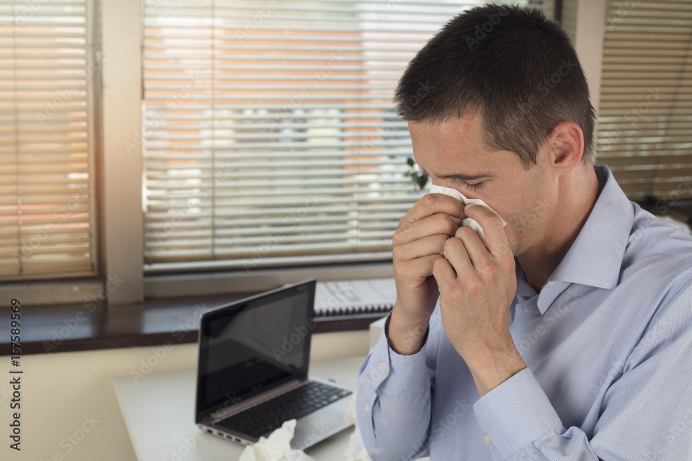 Business man with sneezing in a tissue in an office / workplace. Pollen ...