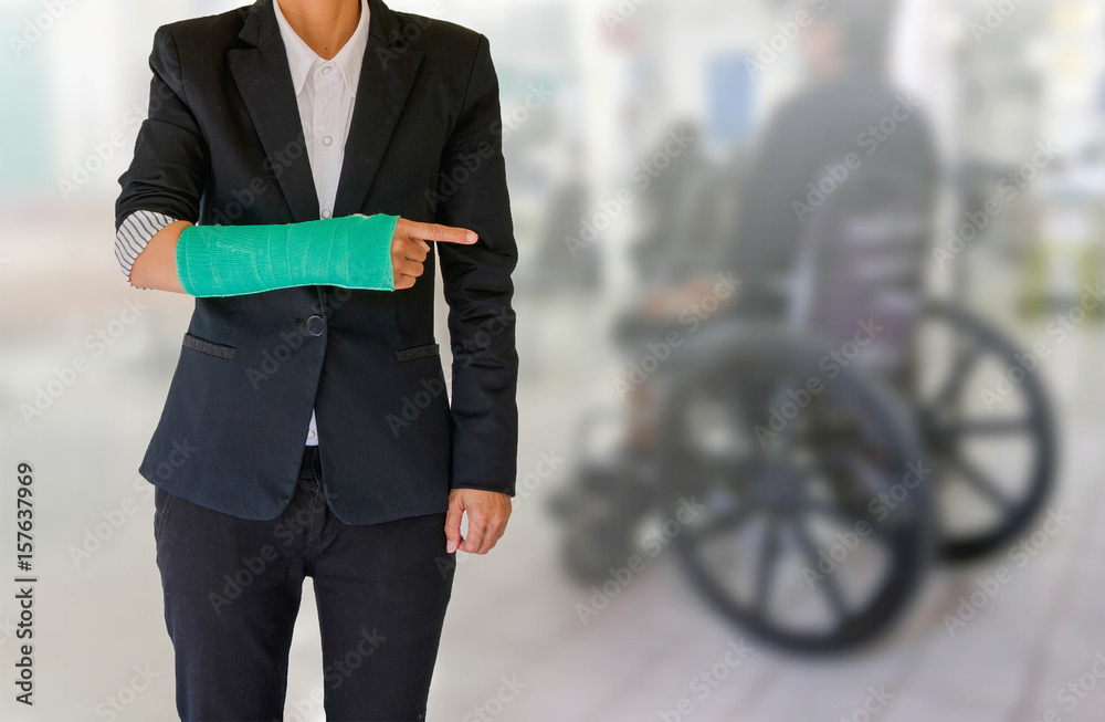 Injured businesswoman with green cast on hand and arm on blurred ...