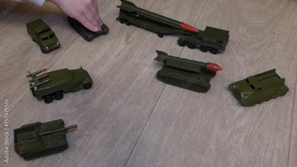 Kid rolls old military vehicles - metal cars colored in khaki. Soviet ...