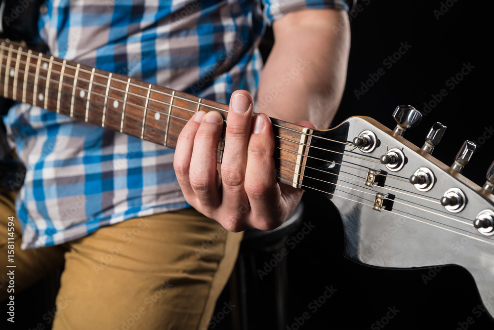 Music and art. Electric guitar in the hands of a guitarist, on a black ...