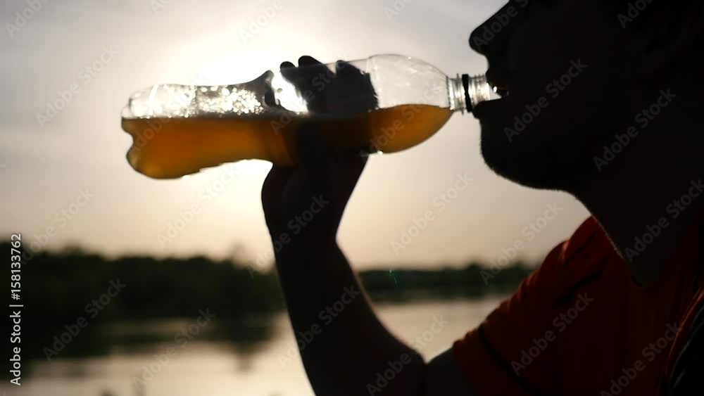 Quench thirst with a foamy drink from a bottle at sunset with ...