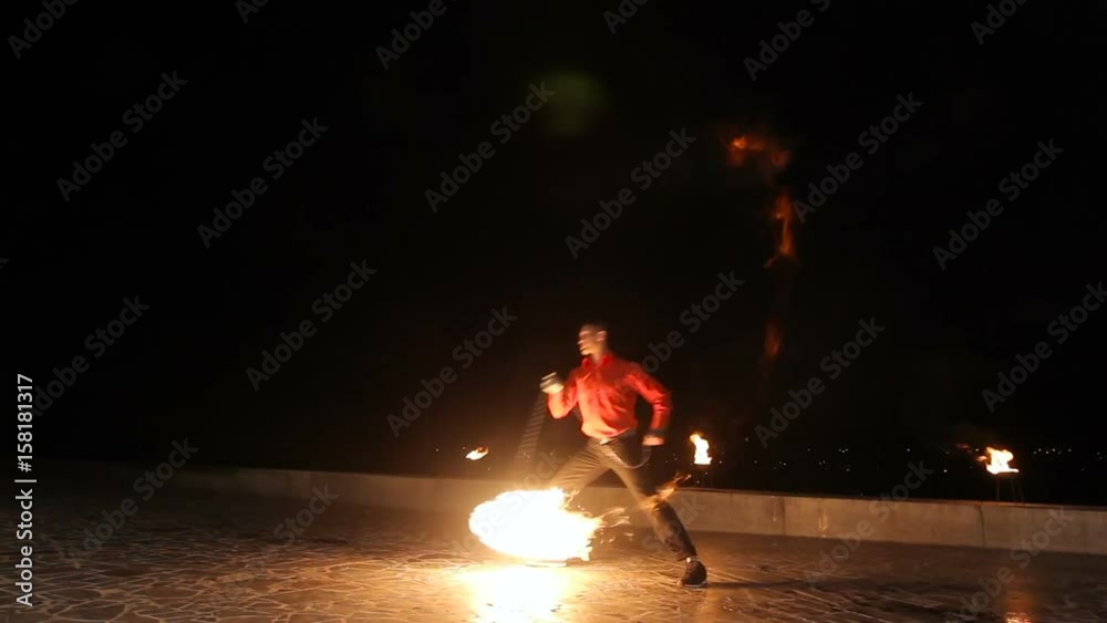 Artist man rotates the fireball.Man twist fiery circles on a fire show ...
