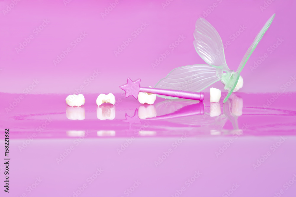 Milk teeth, tooth fairy wing and tooth fairy wand on rose background ...