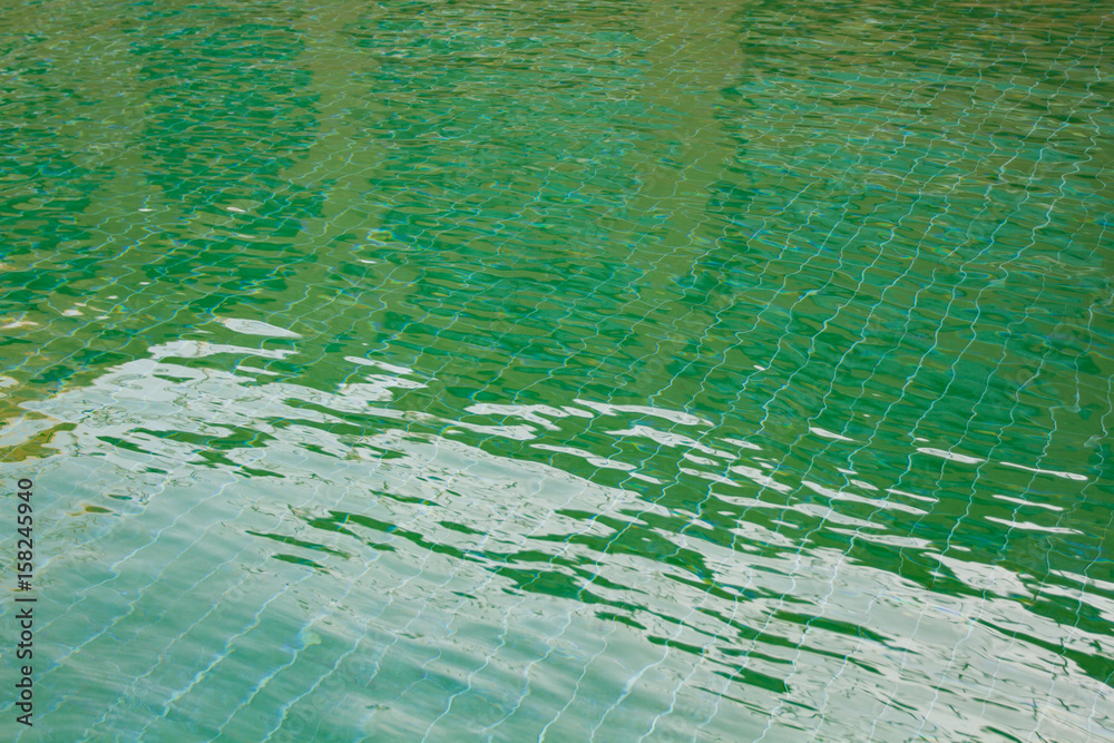 The Sun reflection on the green clear water ripples of swimming pool ...