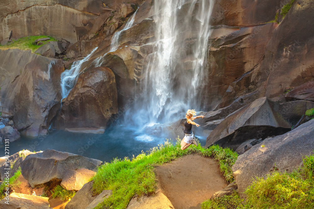 Hiking woman jumping in Yosemite National Park at Vernal Fall on Merced ...