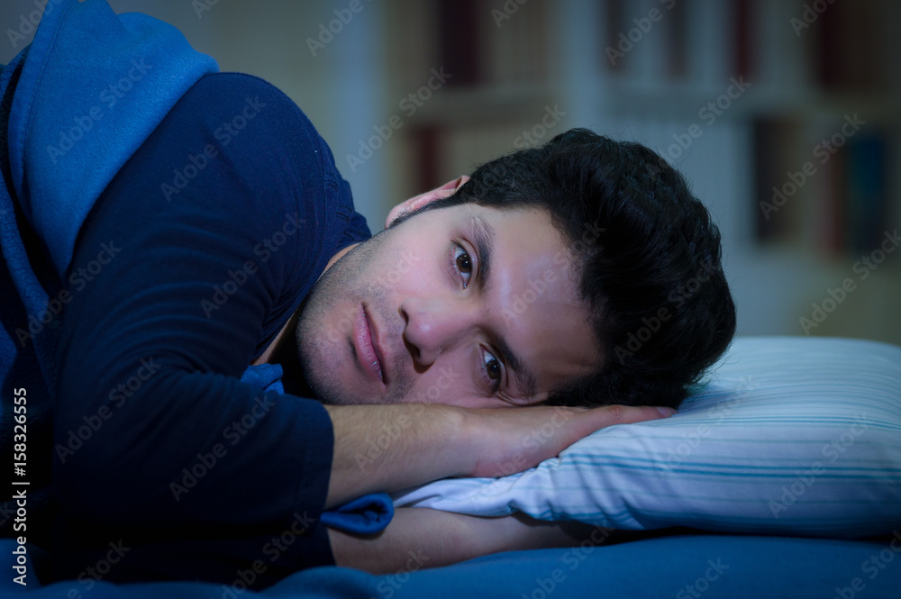 Handsome young man in bed with eyes opened suffering insomnia and sleep ...
