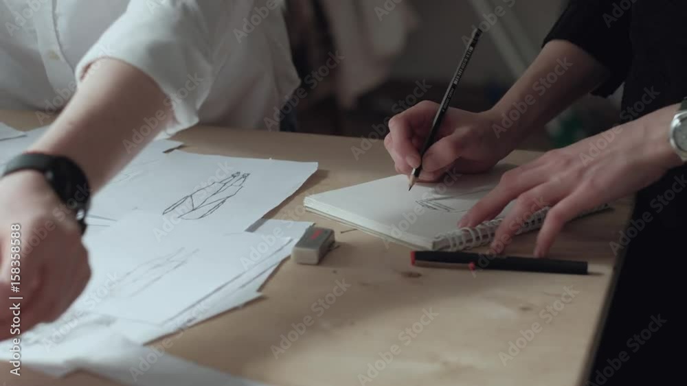 Two Fashion Designers Working in the Studio, Draw a Sketch of Clothes ...