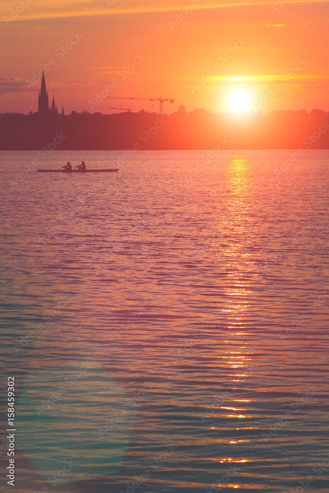 Team work of young men in a row boat silhouetted at sunset. Beautiful ...