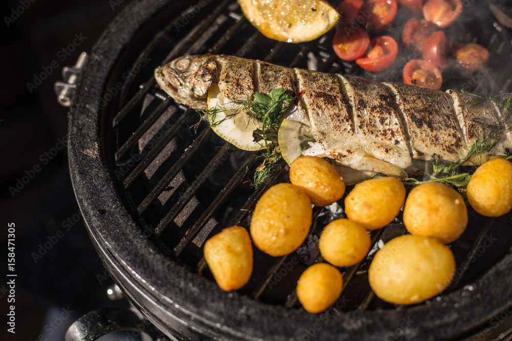Delicious rainbow trout fish with tomatoes, potatoes and lemon cooking ...