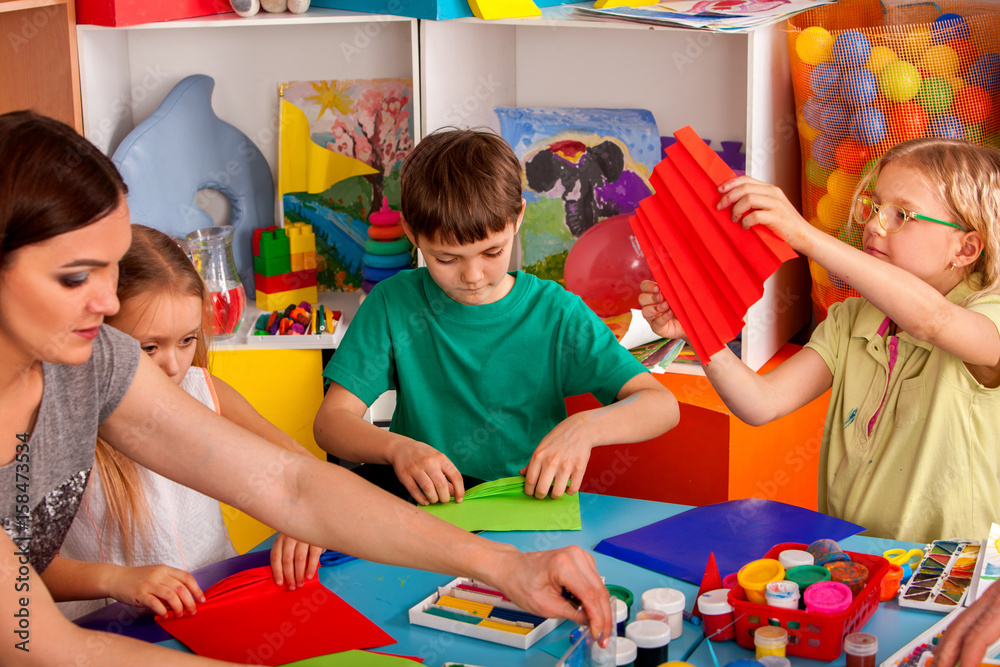 School children with scissors in kids hands cutting paper with teacher ...