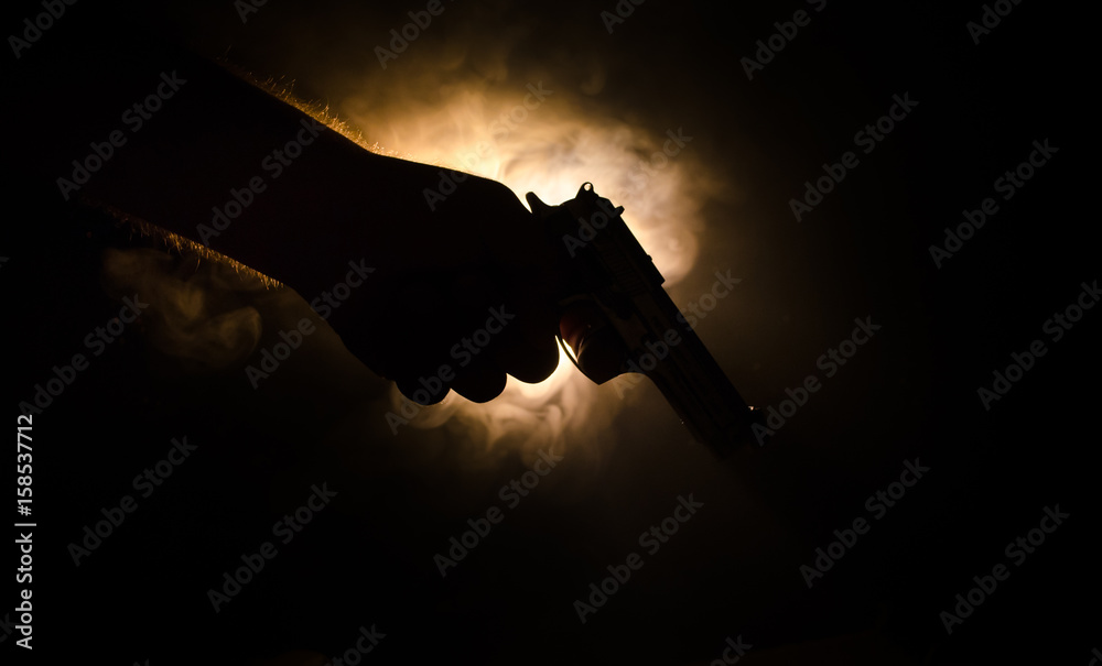 Male hand holding gun on black background with smoke ( yellow orange ...