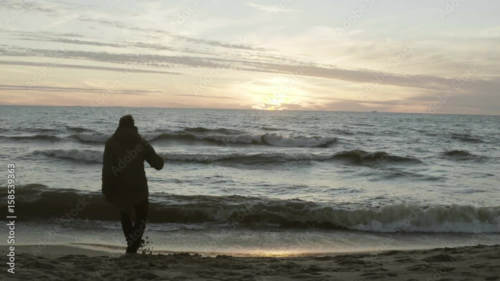 Video Stock Young man throws sand and runs on the shore of the sea. Sad ...