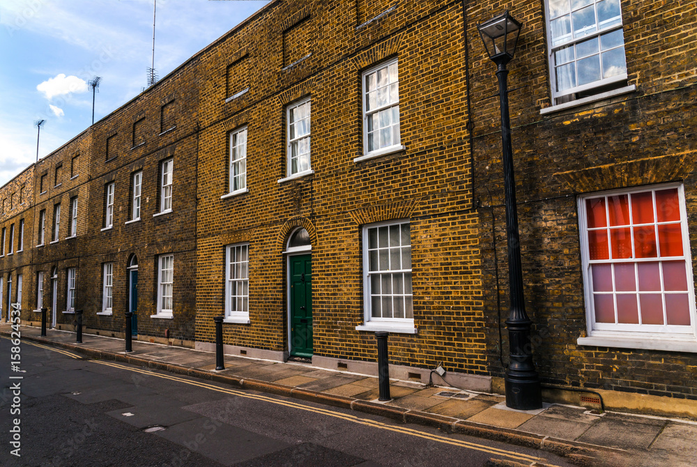 Typical old English buildings, low brick buildings across a narrow ...