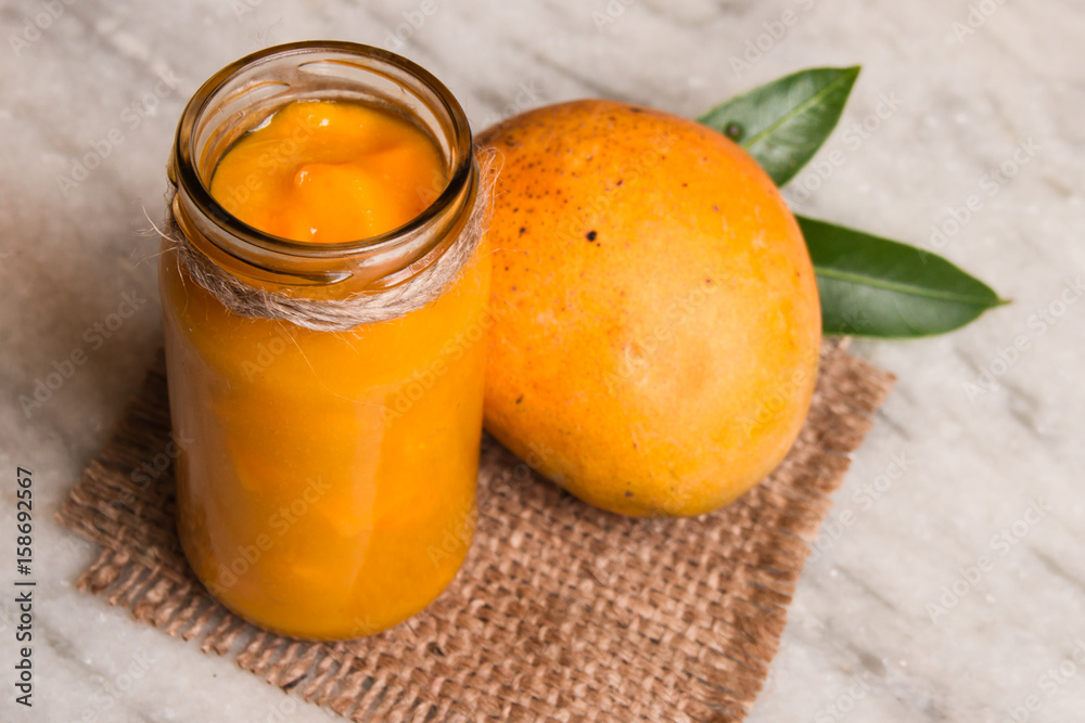 Homemade Mango Jam with fresh fruits and leaves of mango on a white ...